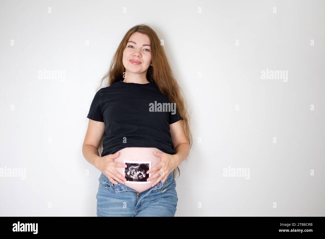 Pregnant Caucasian woman with long hair holding a sonogram picture ...