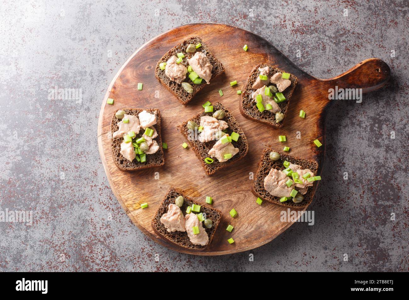 Healthy rye bread with canned cod liver, capers and green onions close ...
