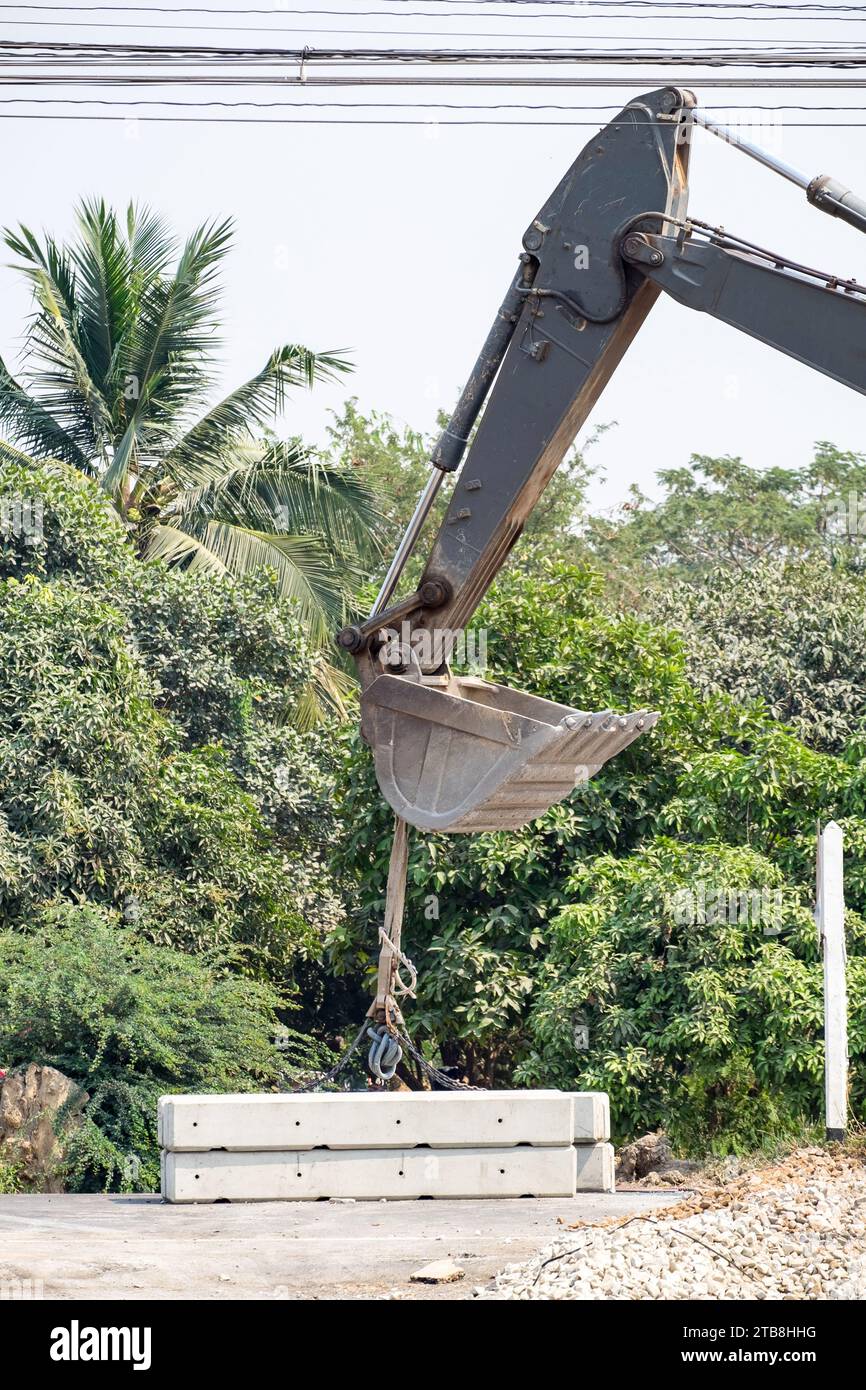Backhoe is working by lifting cement block in construction site Stock ...