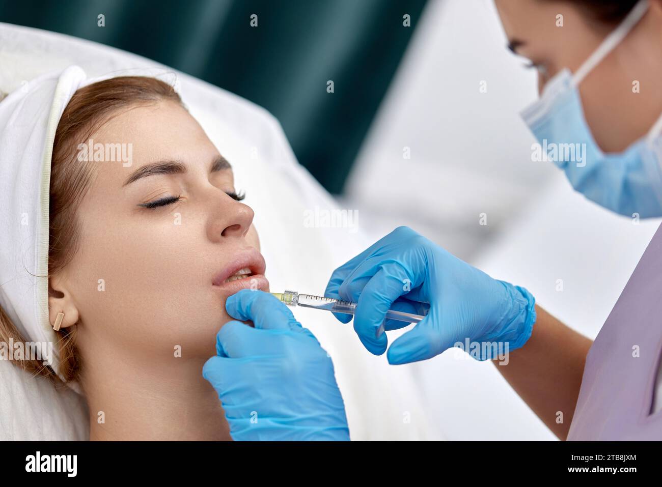 cosmetologist makes injections to enlarge the lips of beautiful woman ...
