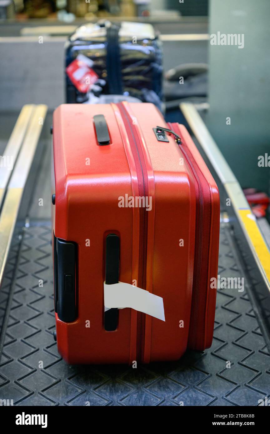 Red luggage on conveyor belt for check and scan on counter check-in at ...