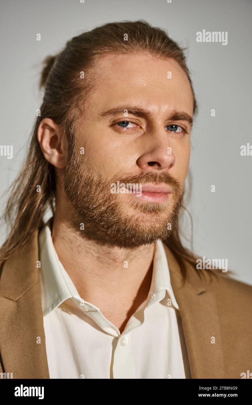 portrait of good looking businessman in shirt and beige blazer on grey ...