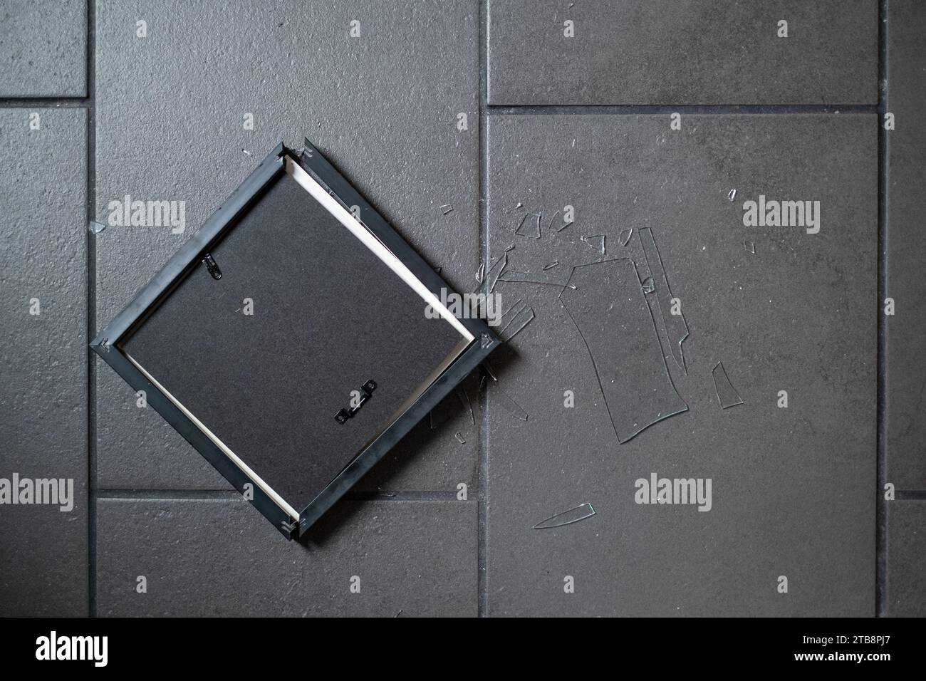 A broken picture frame on a tiled floor, with the frame itself broken ...