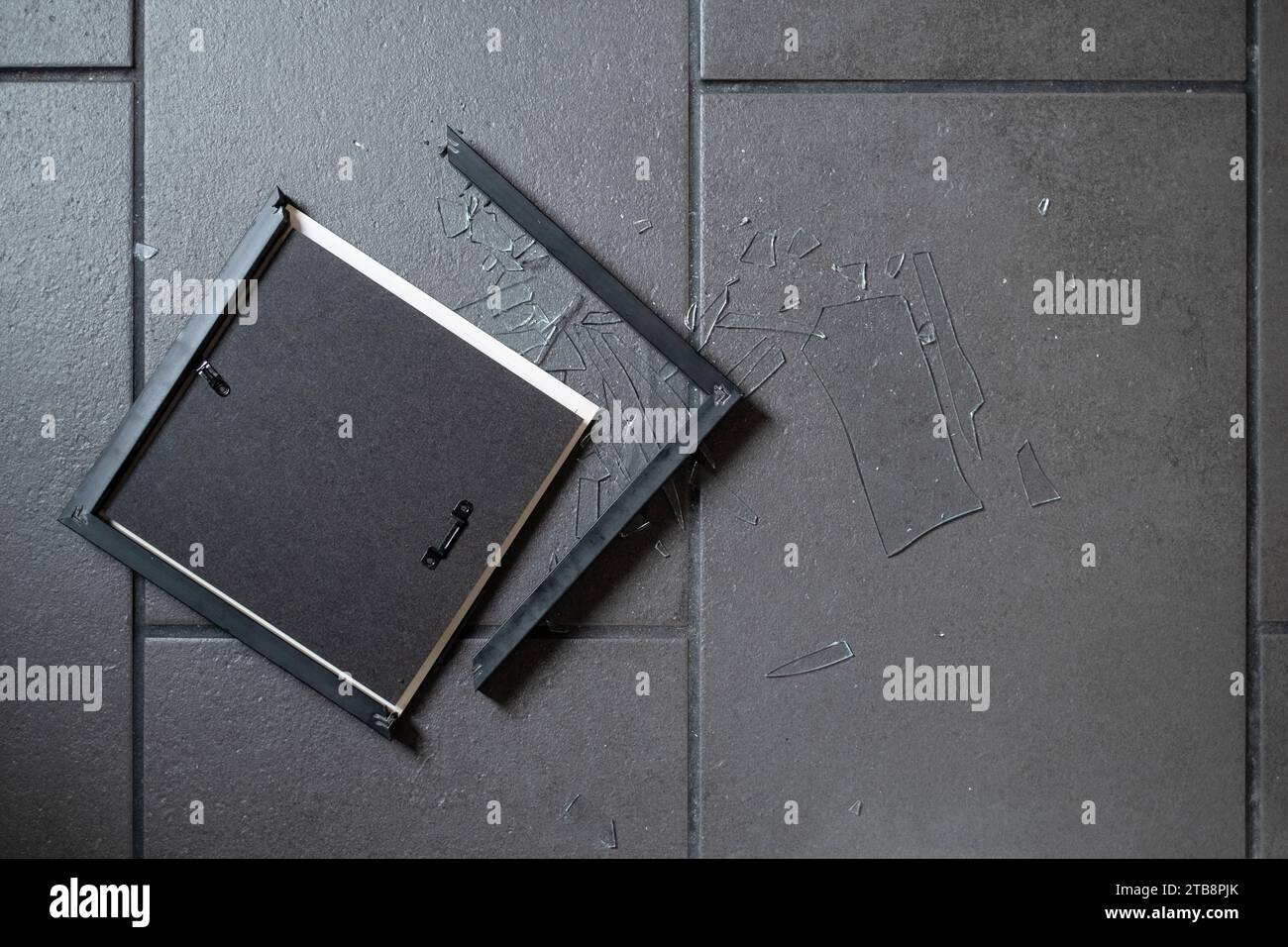 A broken picture frame on a tiled floor, with the frame itself broken ...