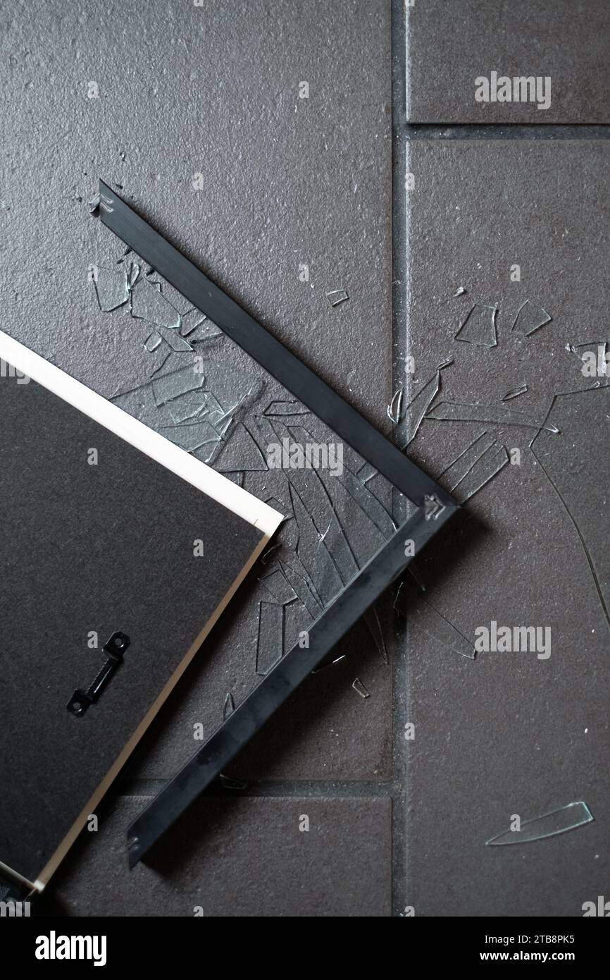 A broken picture frame on a tiled floor, with the frame itself broken ...