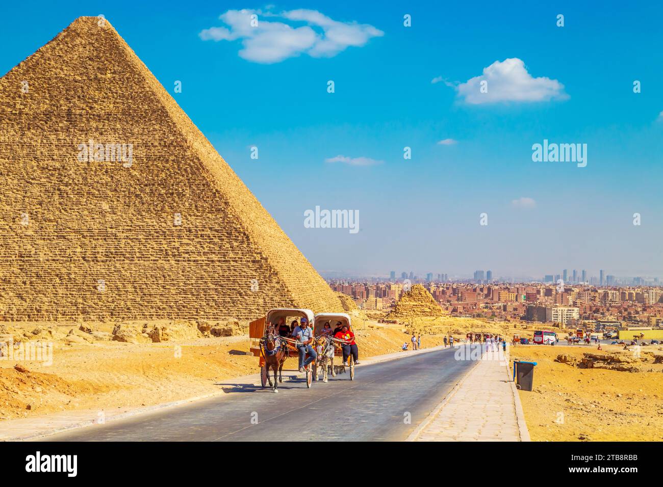 Horse-drawn carriages carry tourists near the Great Pyramids of Egypt ...