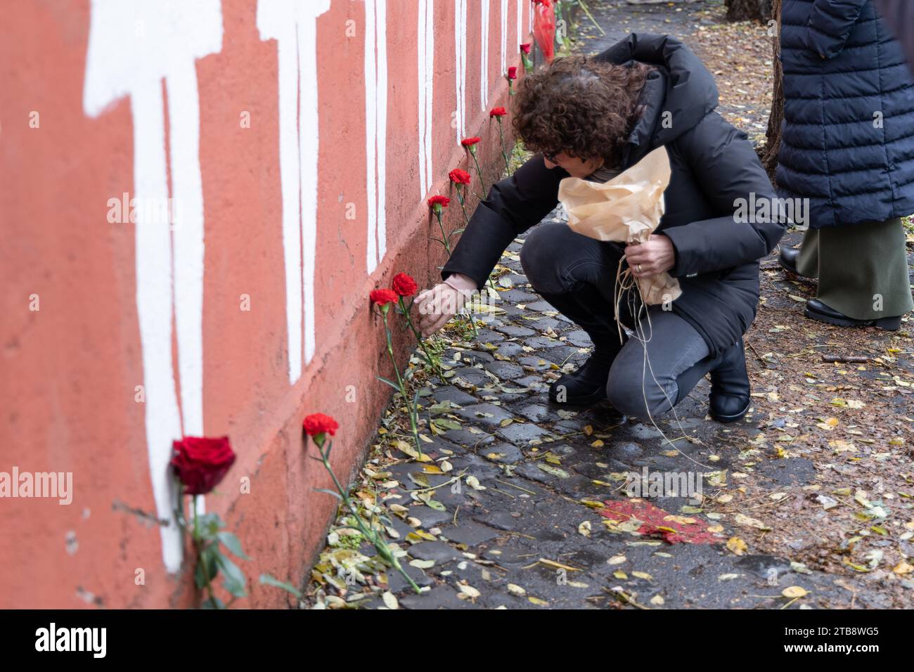 Rome, Italy. 05th Dec, 2023. A woman places a red flower at the base of ...