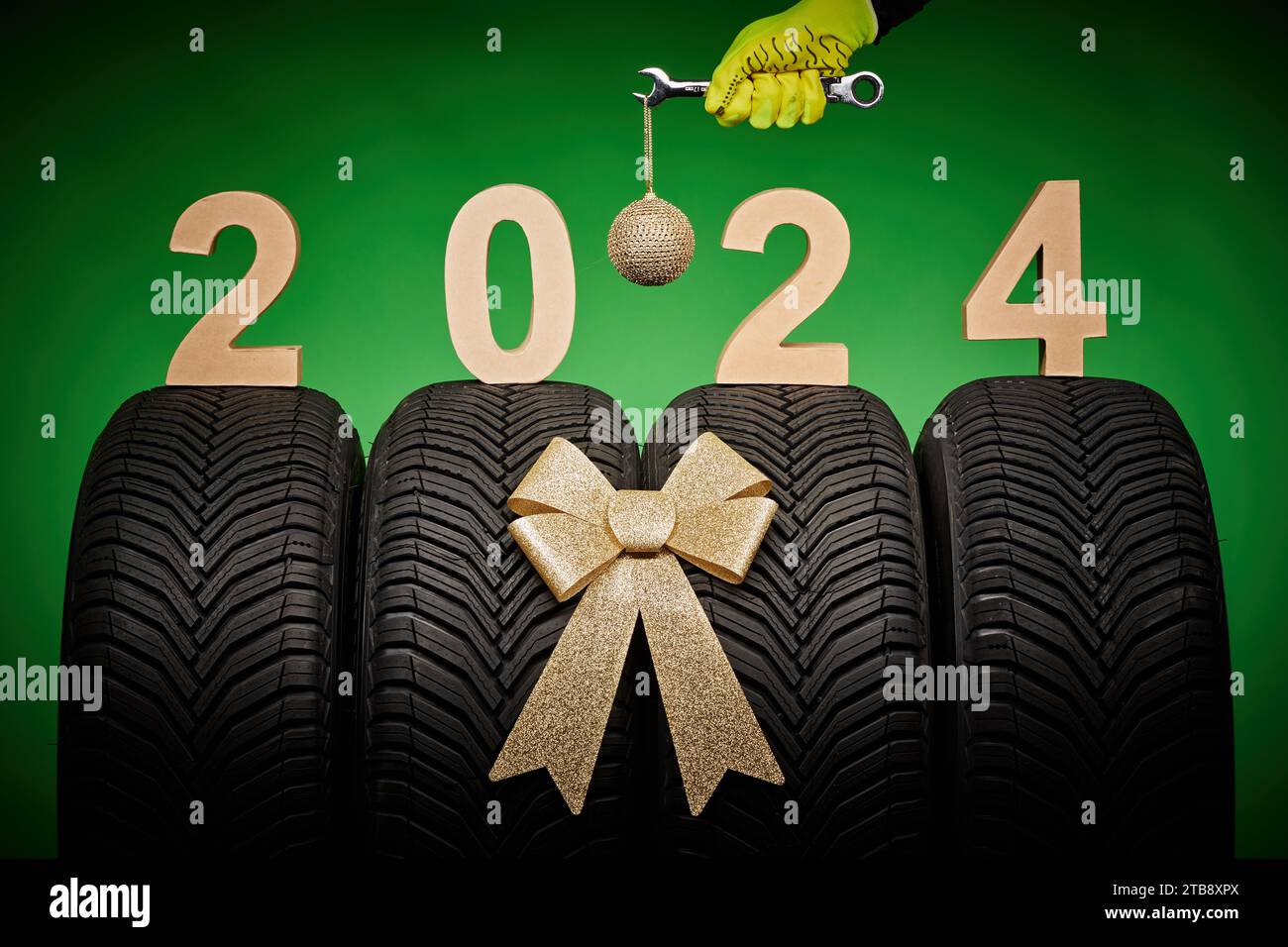 Winter car tires mechanic hand with wrench tool and christmas tree ball ...