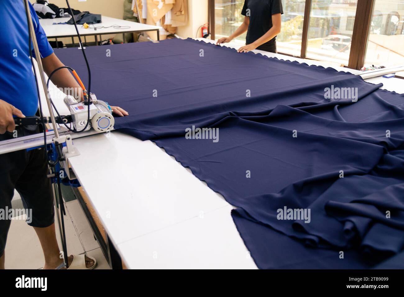 Person cutting fabric with machine for production of garment products Stock Photo - Alamy