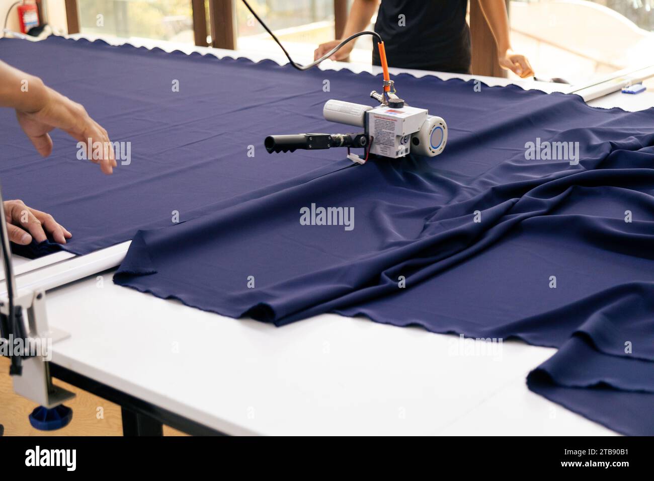 Person cutting fabric with machine for production of garment products ...