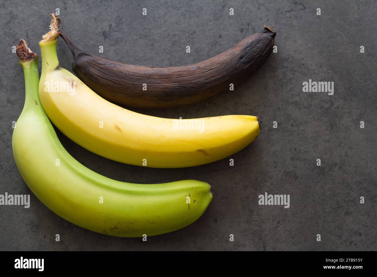 Green, yellow and brown banana on dark background, three level of ...