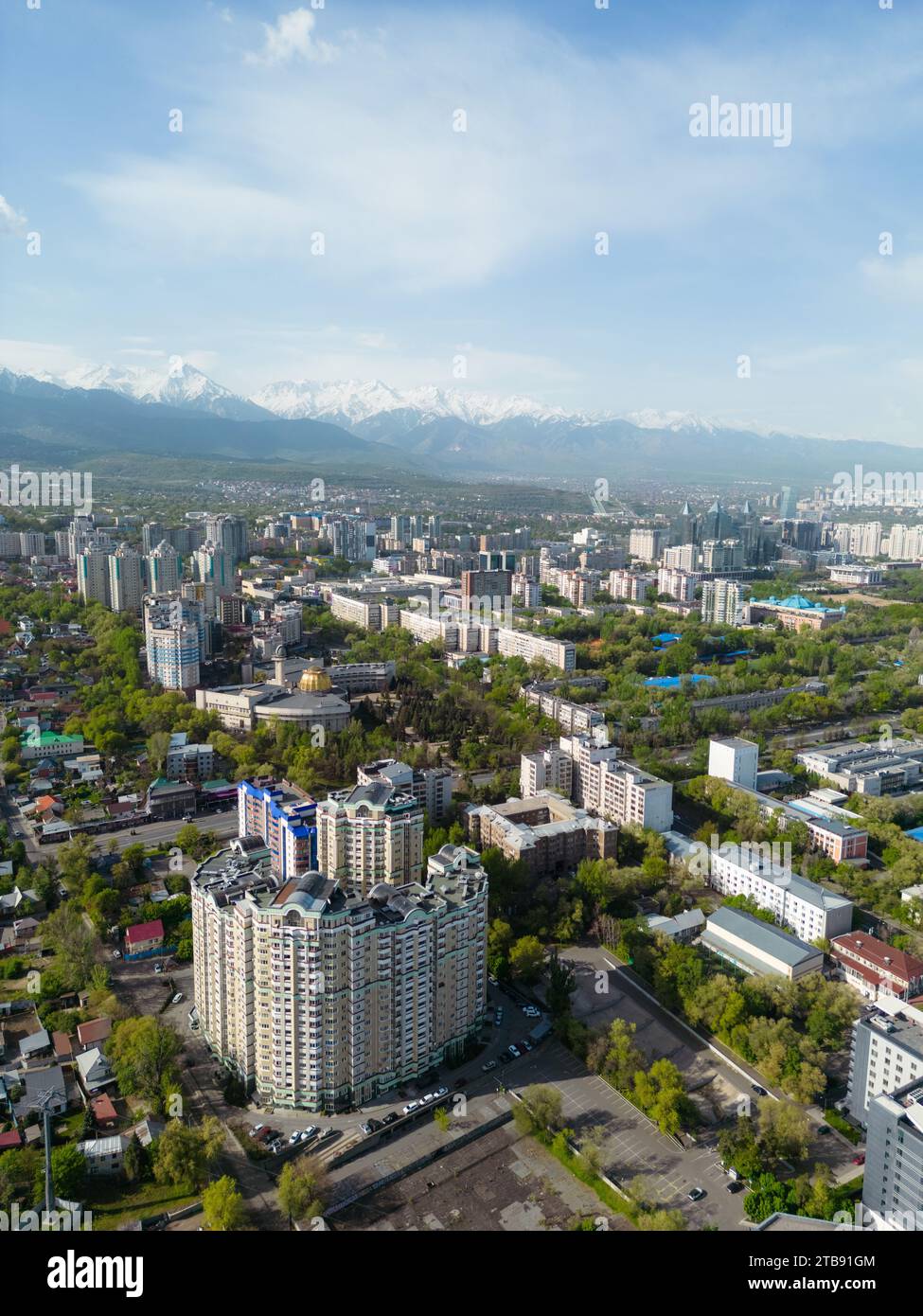 Aerial view of Almaty city during sunny spring day with snow capped ...