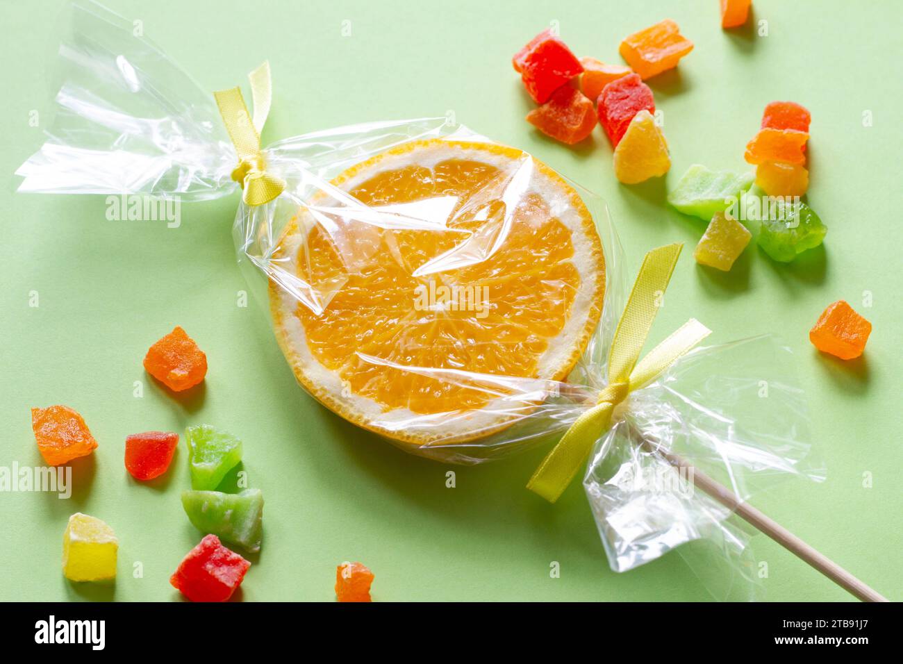 Orange slice on stick wrapped in foil and candied fruit, fruit lollipop ...