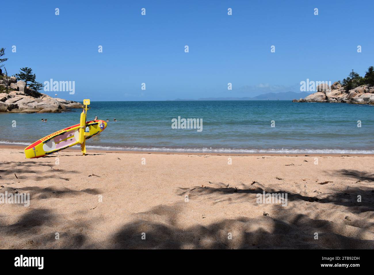 Lifeguard paddle board on the beach with people swimming in the sea ...