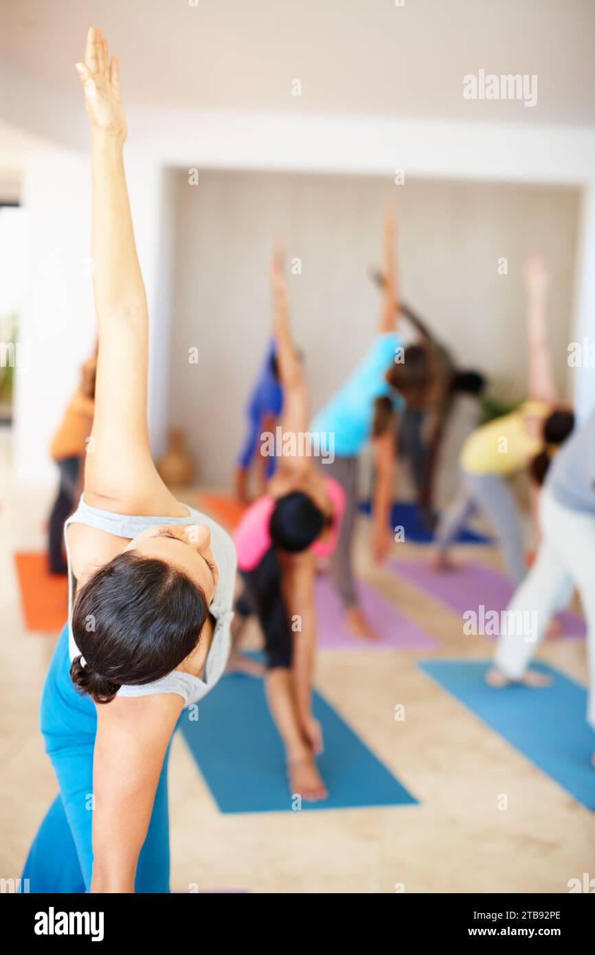 Yoga class, stretching and people in trikonasana pose at gym, exercise ...