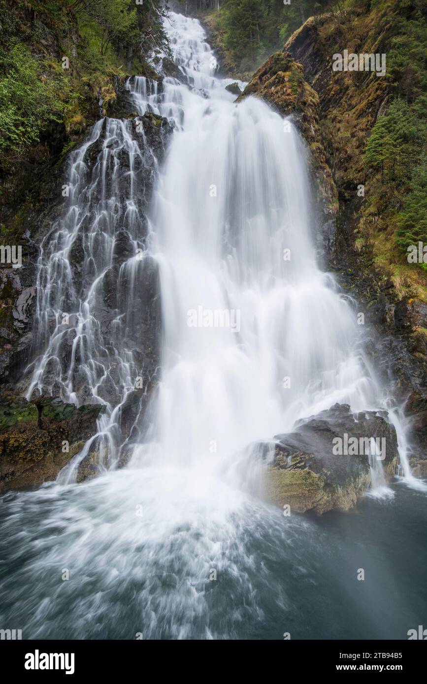 Waterfall cascading down a rugged cliff into the ocean at Red Bluff Bay ...