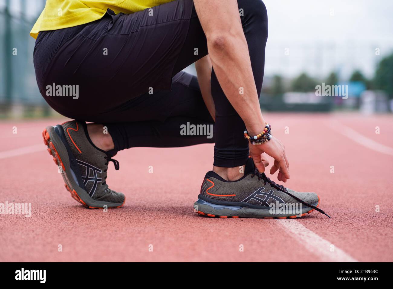 closeup of athlete man taking a break from training, tying his sneaker ...