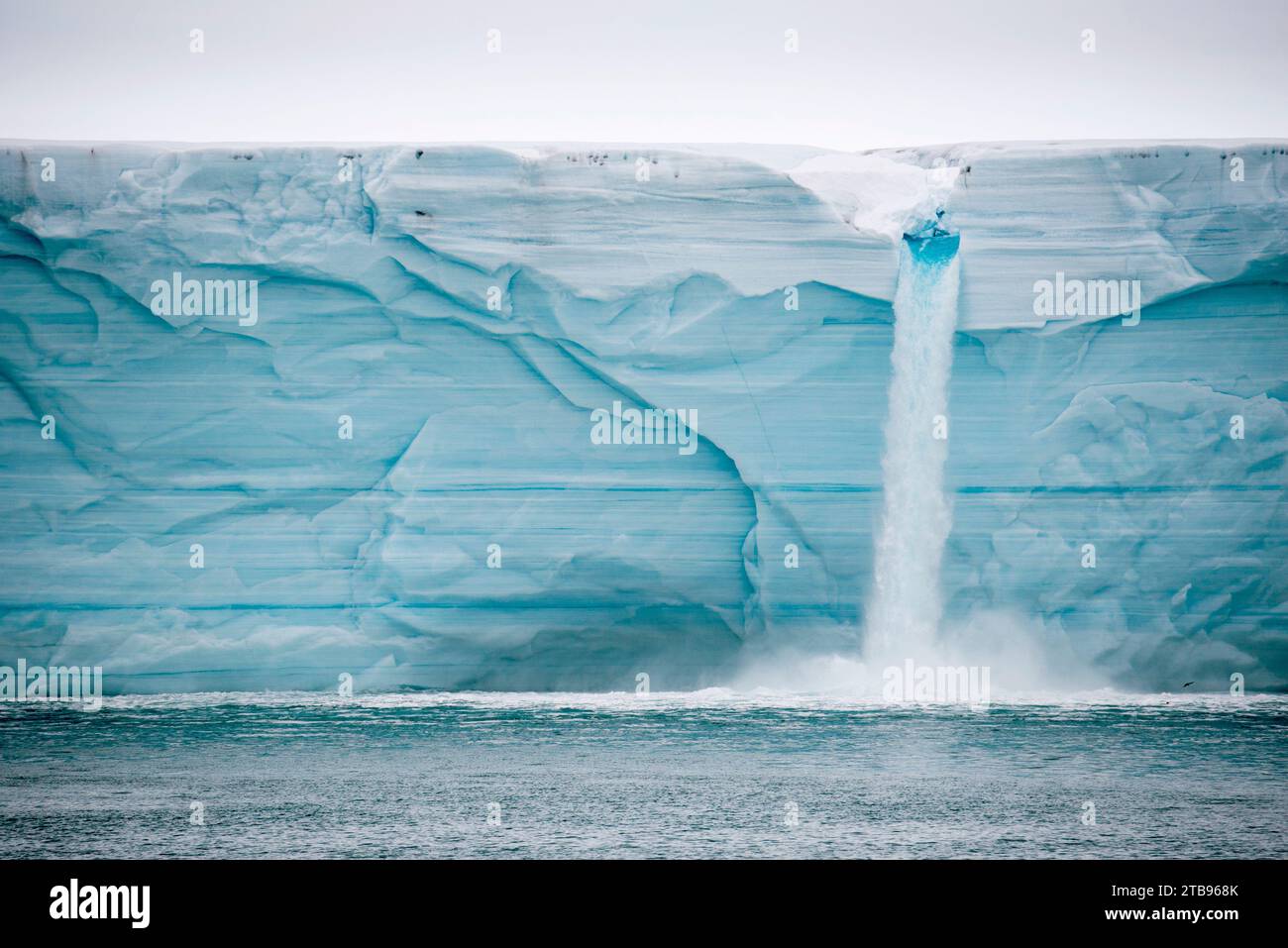 Meltwater pours over an ice cliff from the surface of the ...