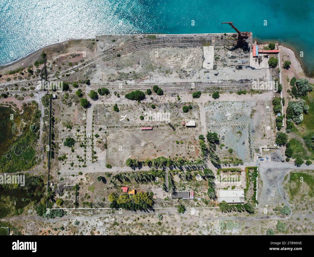Aerial view of abandoned port with rusted quay cranes on a lake shore ...