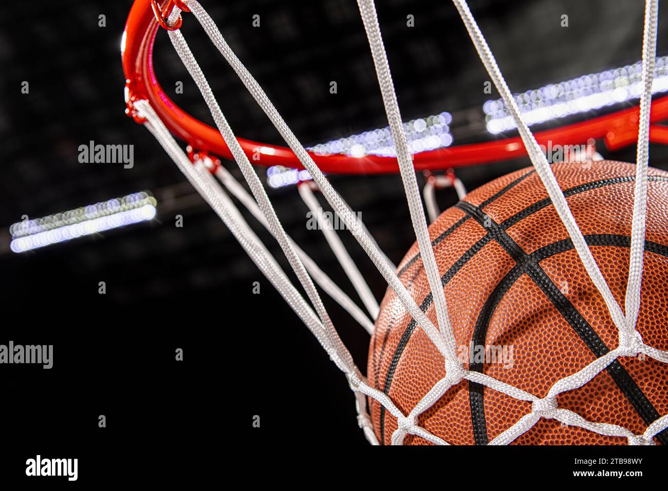 A close-up view of a basketball falling through the rim and nylon net ...