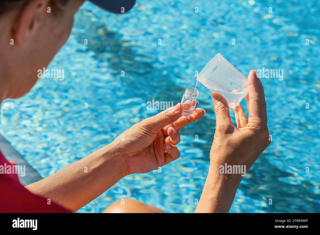 Close-up of hands pouring water into testing vial for PH value test ...