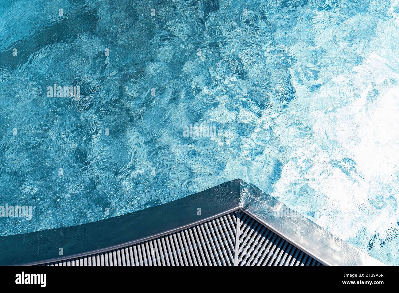 Overhead view of pool corner with textured blue water and grating edge ...