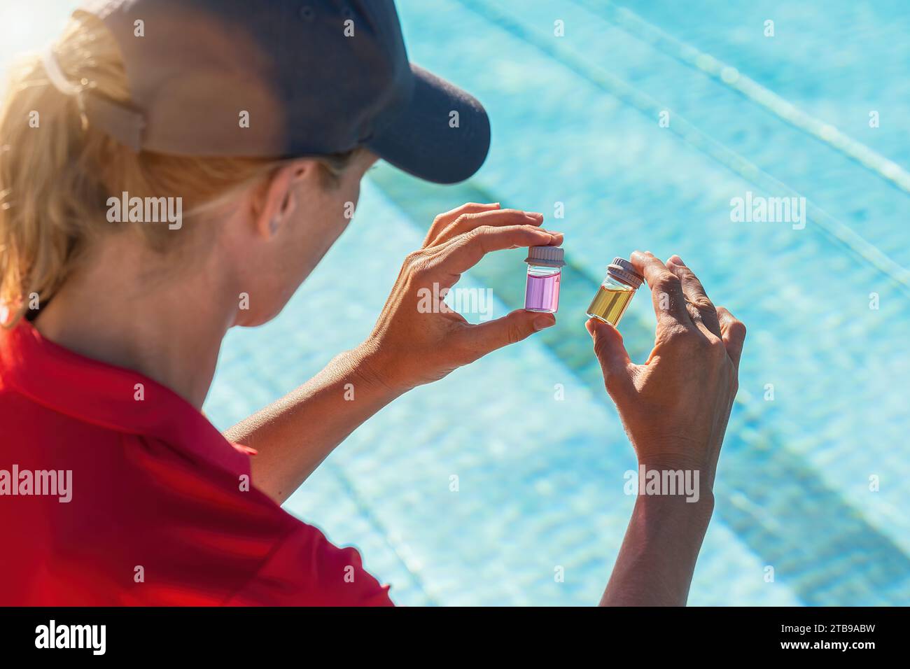 Woman comparing water samples in vials for pH testing against pool ...