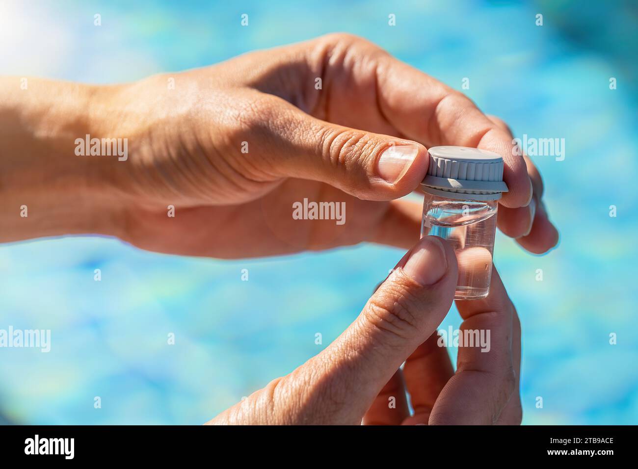 Close-up Hands closing a vial of water for pH testing near a swimming ...