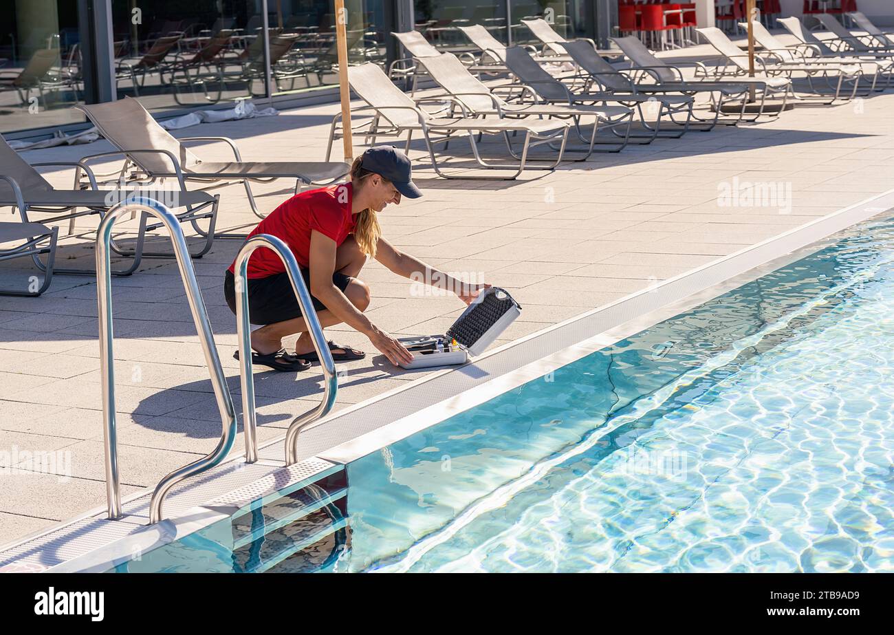 Lifeguard kneeling by the pool with a water testing kit Stock Photo - Alamy
