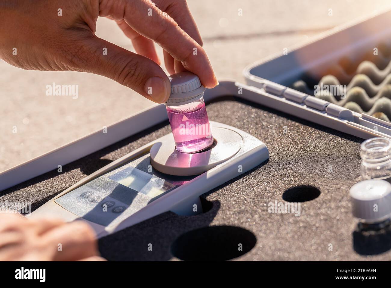 Hand placing a pink liquid bottle on a digital analysis device in a ...