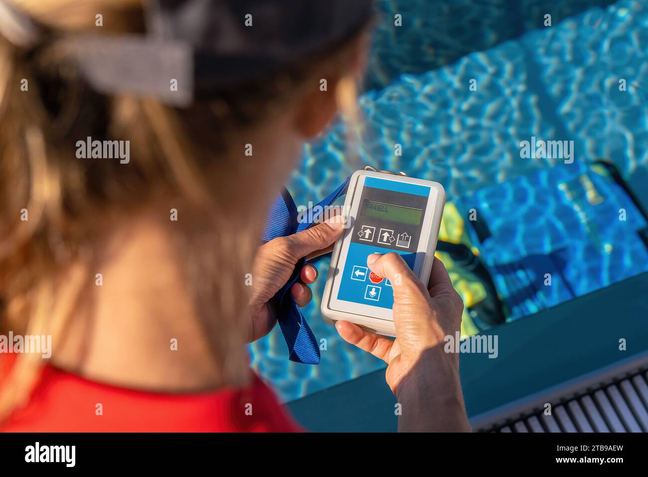 Over-the-shoulder view of a person using a remote control for a pool ...