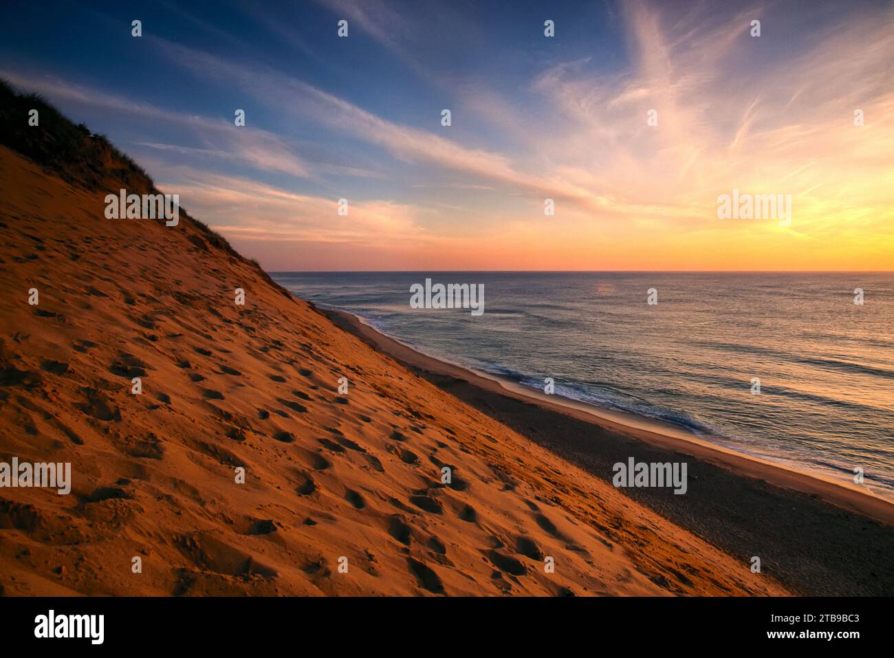 Sunrise paints the sky orange over the shoreline of Coastguard Beach ...
