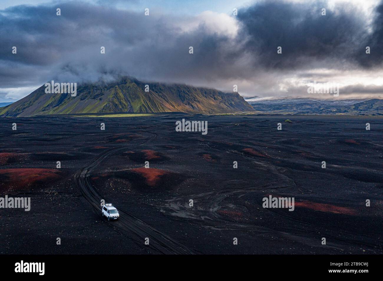 birdseye view of a white offroad camping bus in the black lava ...