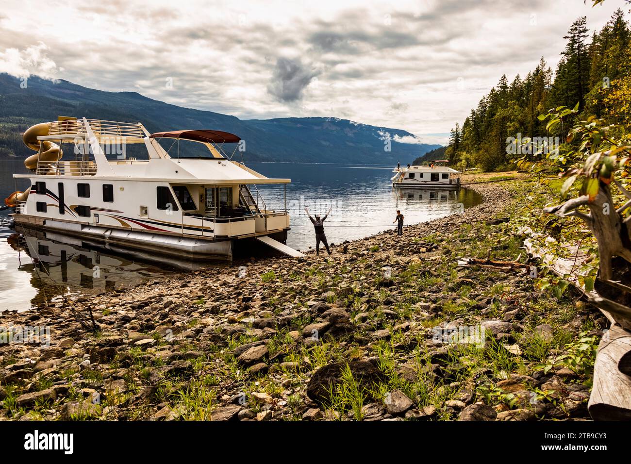 A family enjoying a houseboat vacation while parked on the shoreline of ...
