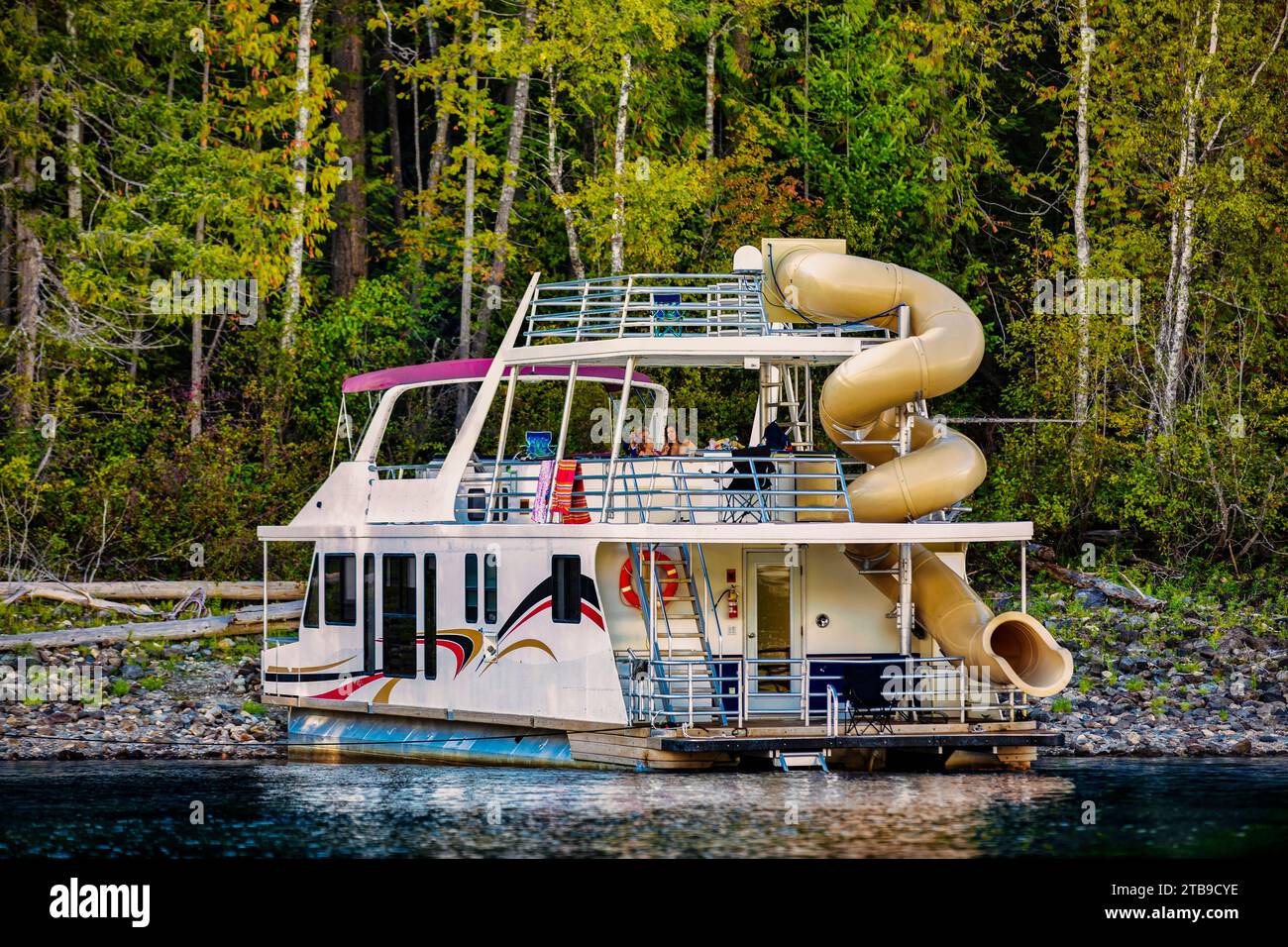 A family enjoying a houseboat vacation while parked on the shoreline of ...