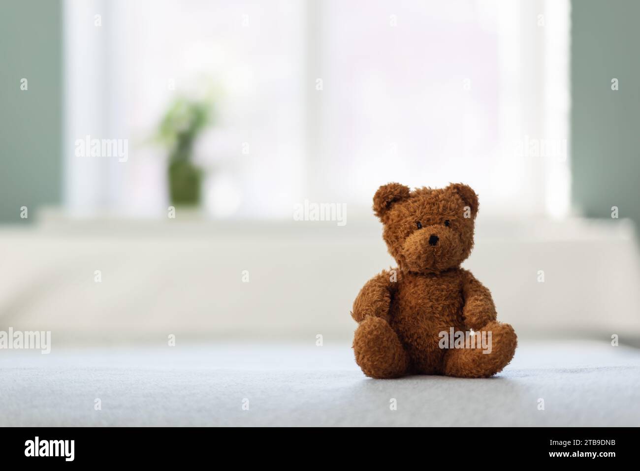 Tiny plush teddy bear toy sitting on the bed. Happy childhood concept ...