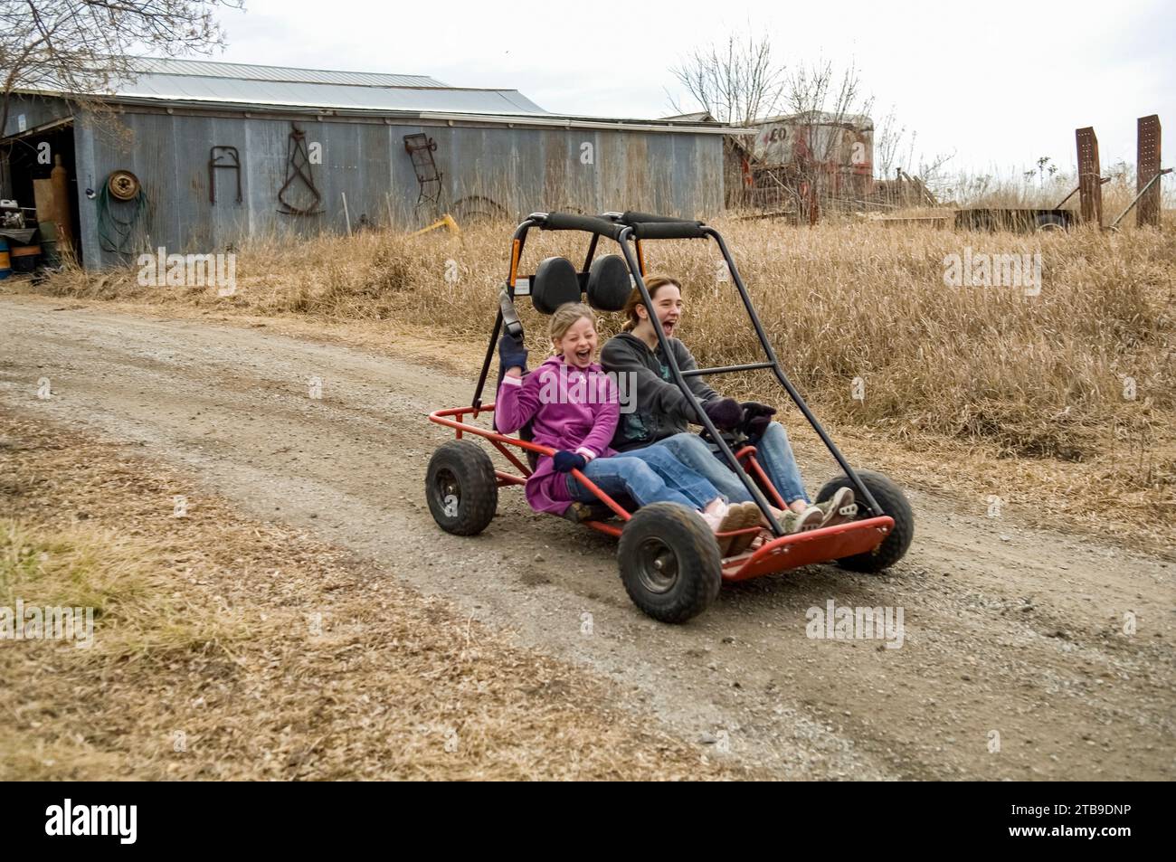 Two girls roll down a hill in a go-cart on a farm; Lincoln, Nebraska ...