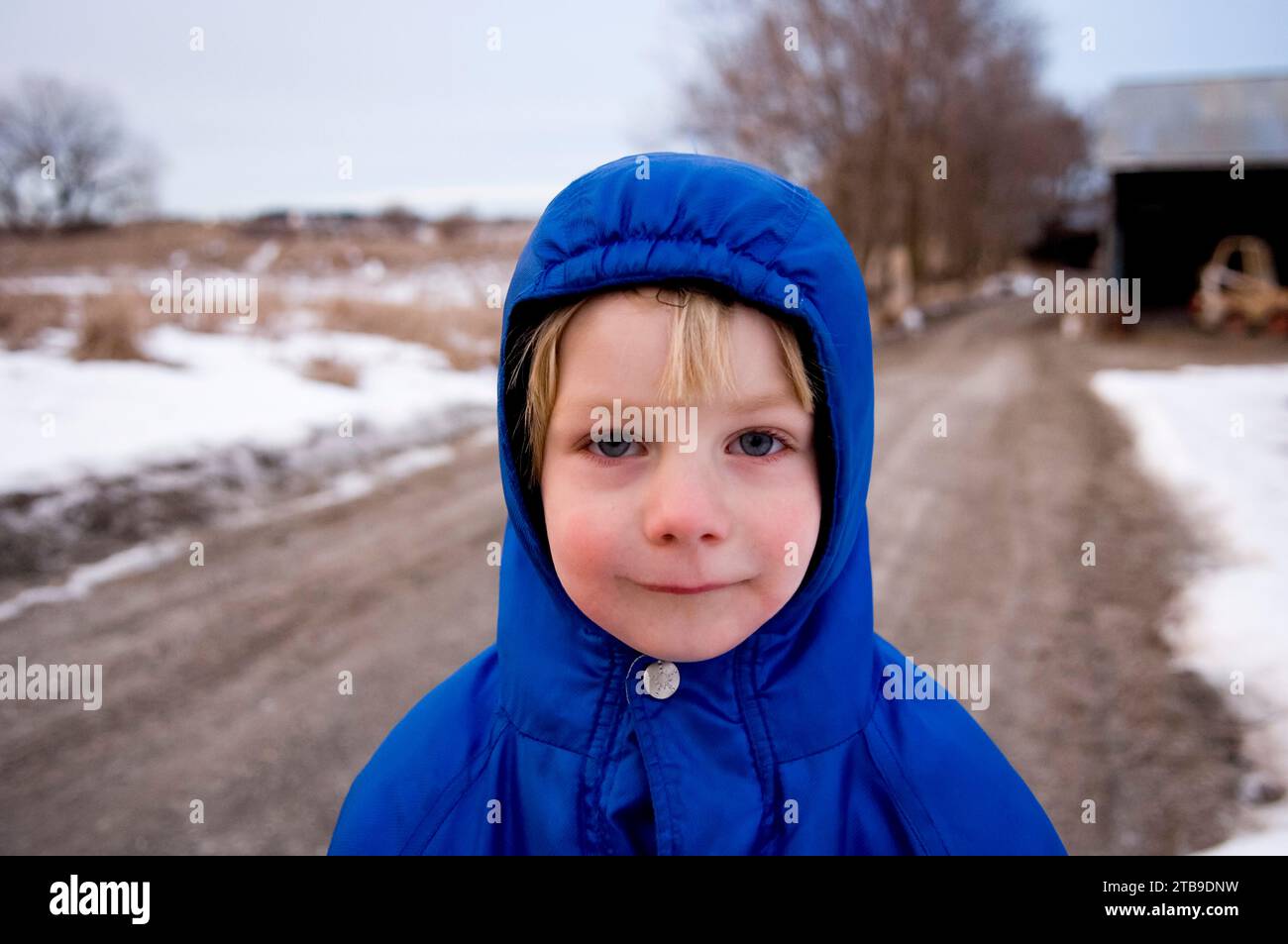 Young boy stands on a farm road in a cold Nebraska winter; Cortland ...