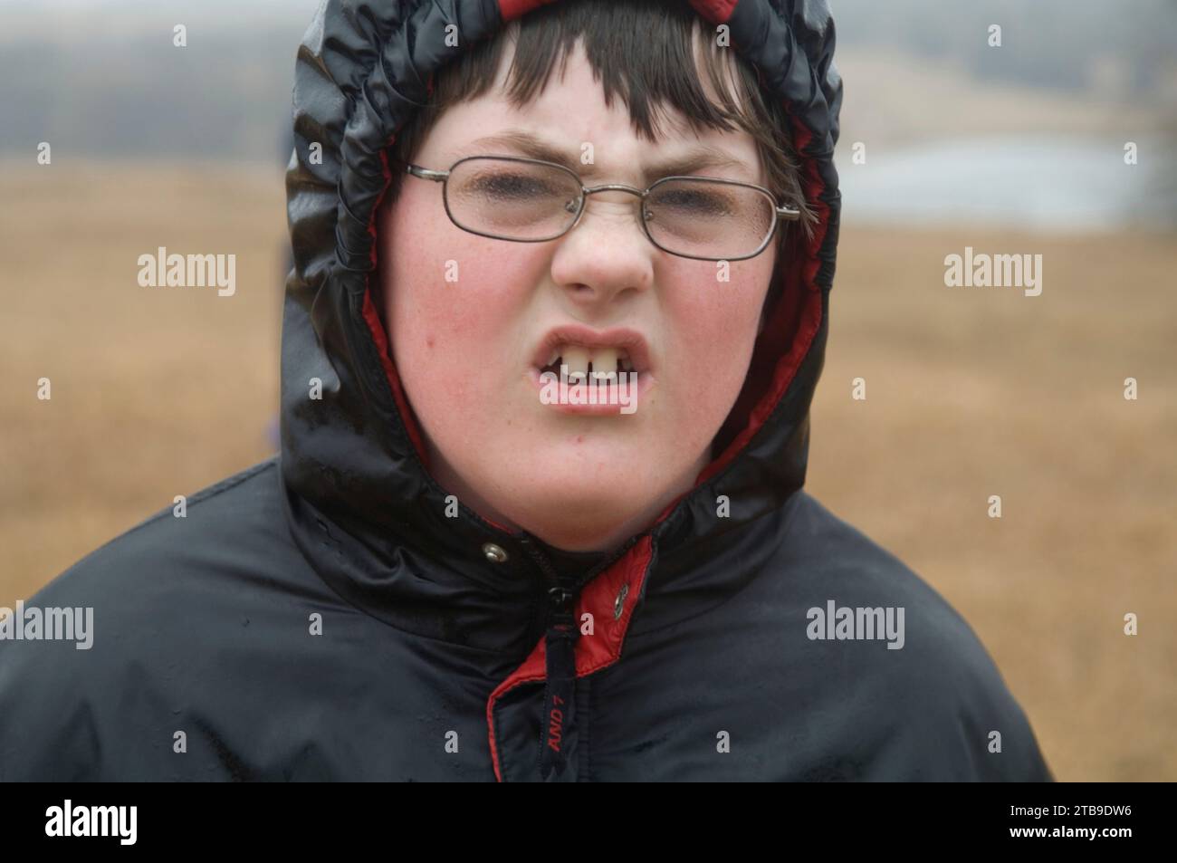 Boy standing outside in a foggy field with his hood up, looking at the ...