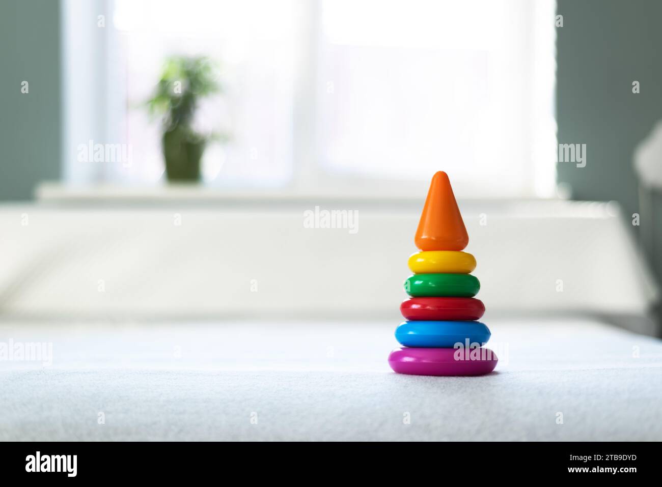 Multi-colored plastic pyramid toy in child playing room. Happy ...