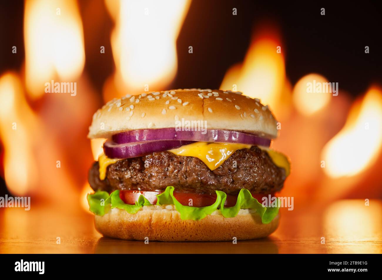 Juicy fresh cheeseburger on BBQ grill fire background. Burning burger ...