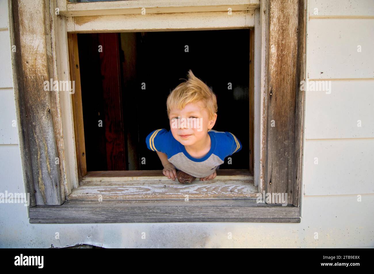 Young boy looks out the window of an old farmhouse; Schuyler, Nebraska ...