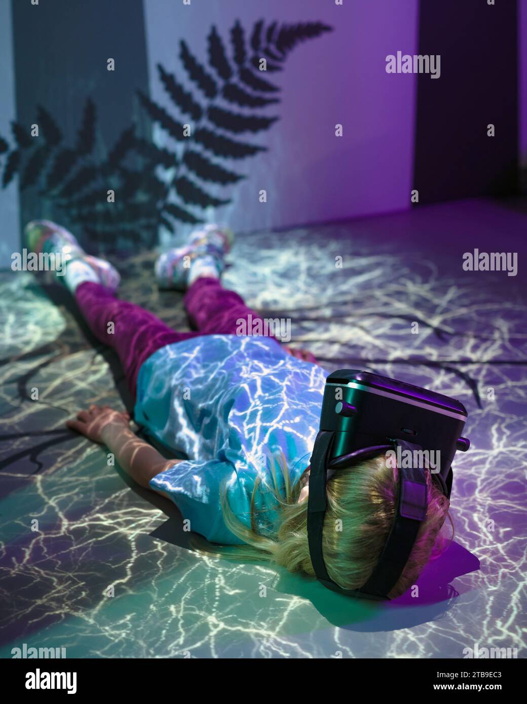 Child girl with virtual reality glasses laying on the VR room floor ...