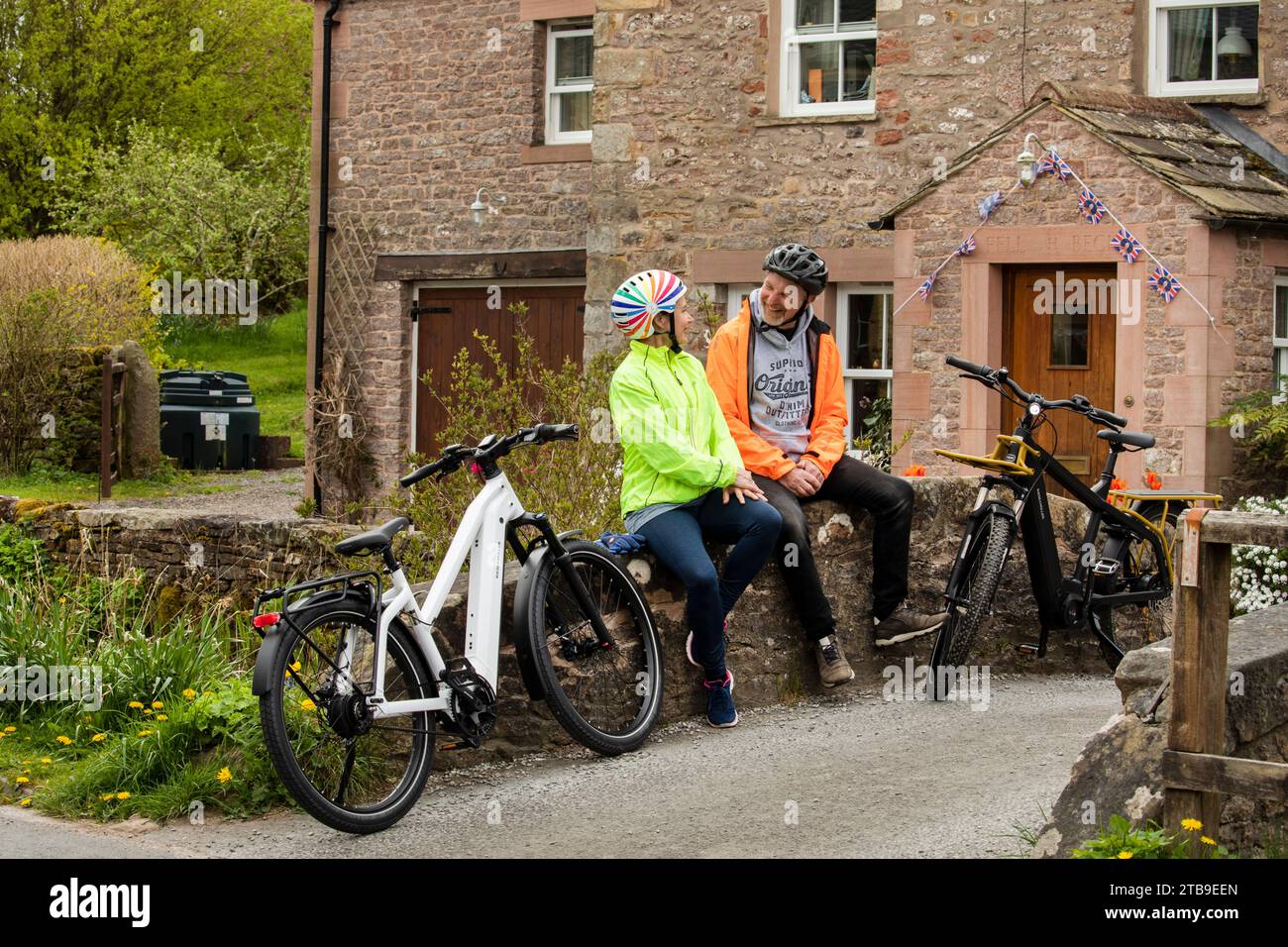 Man and woman cyclists riding electric e bikes in a pretty village in ...