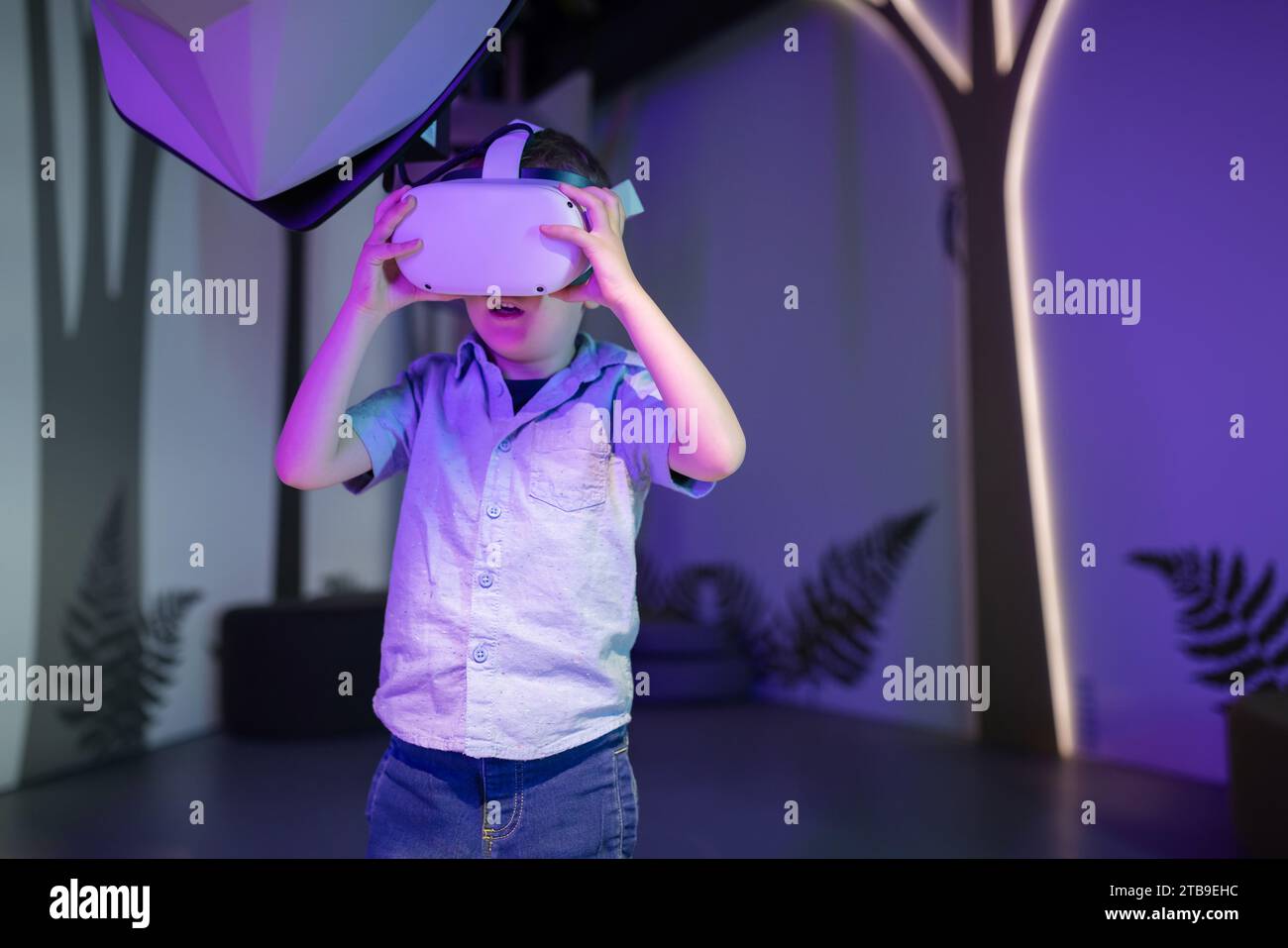 Little boy wearing VR headset in the museum playroom, engaged exploring ...