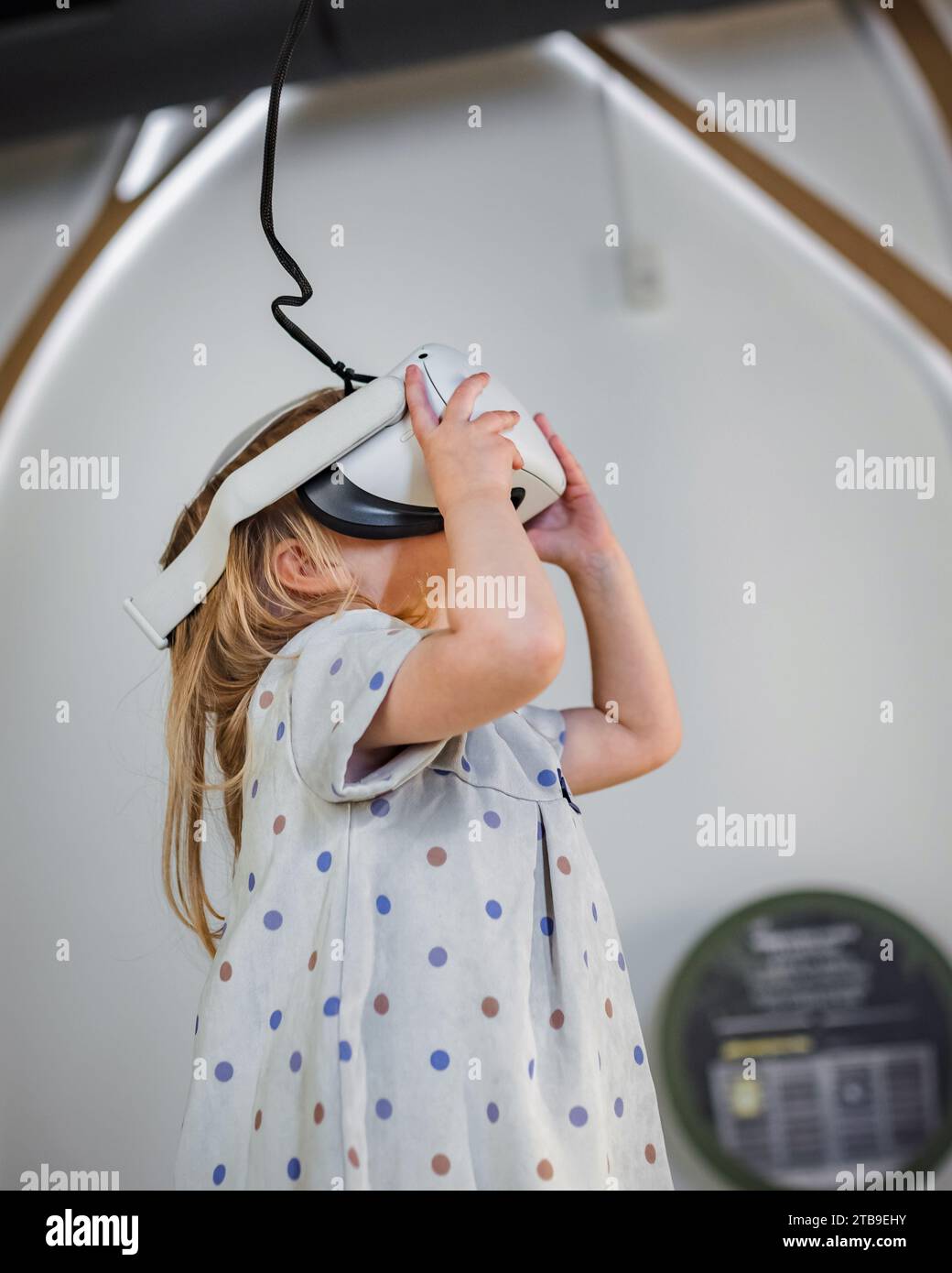 Adorable toddler girl with a virtual reality headset standing in a ...
