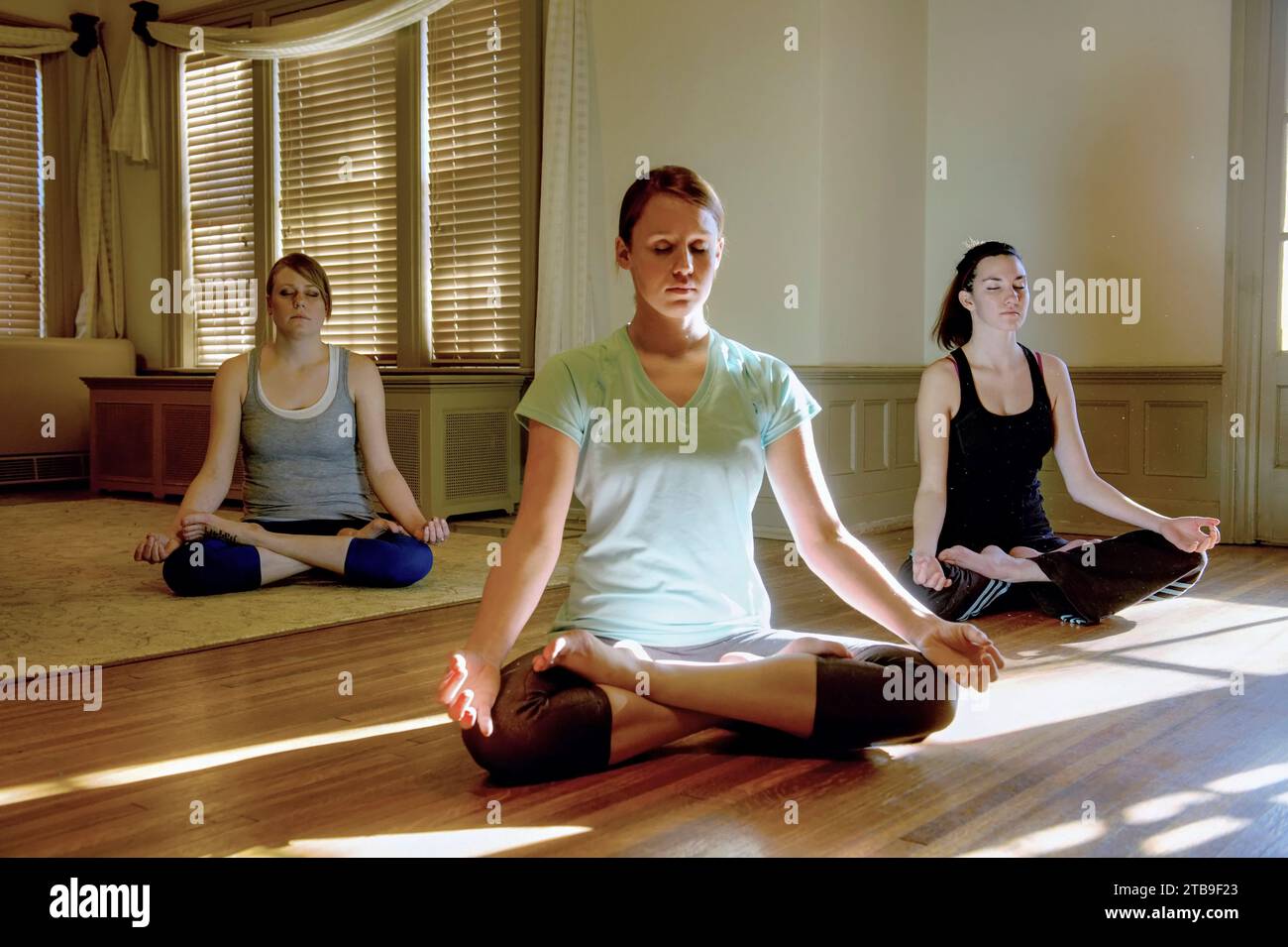Three young woman meditate in the last rays of the setting sun; Lincoln ...