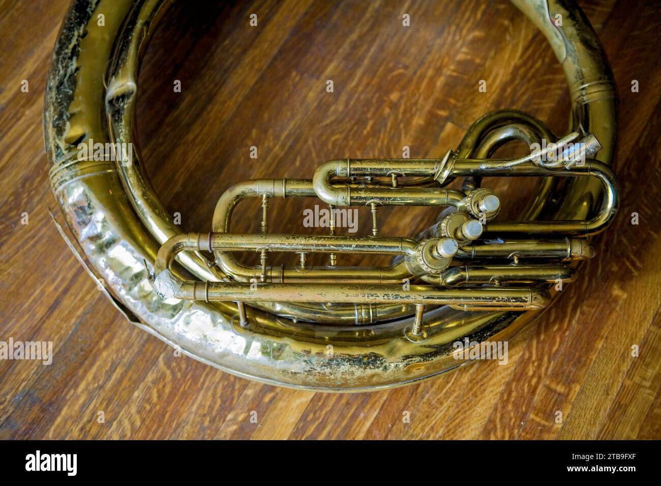 Antique tuba rests against a wood floor; Lincoln, Nebraska, United ...