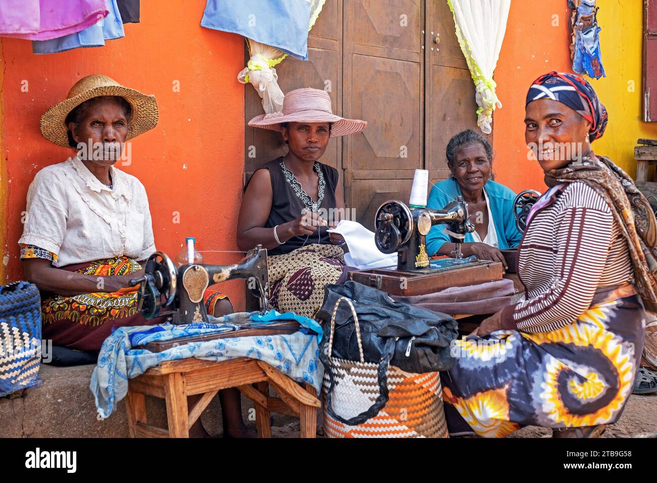 Seamstresses repairing clothes with antique sewing machines on street ...