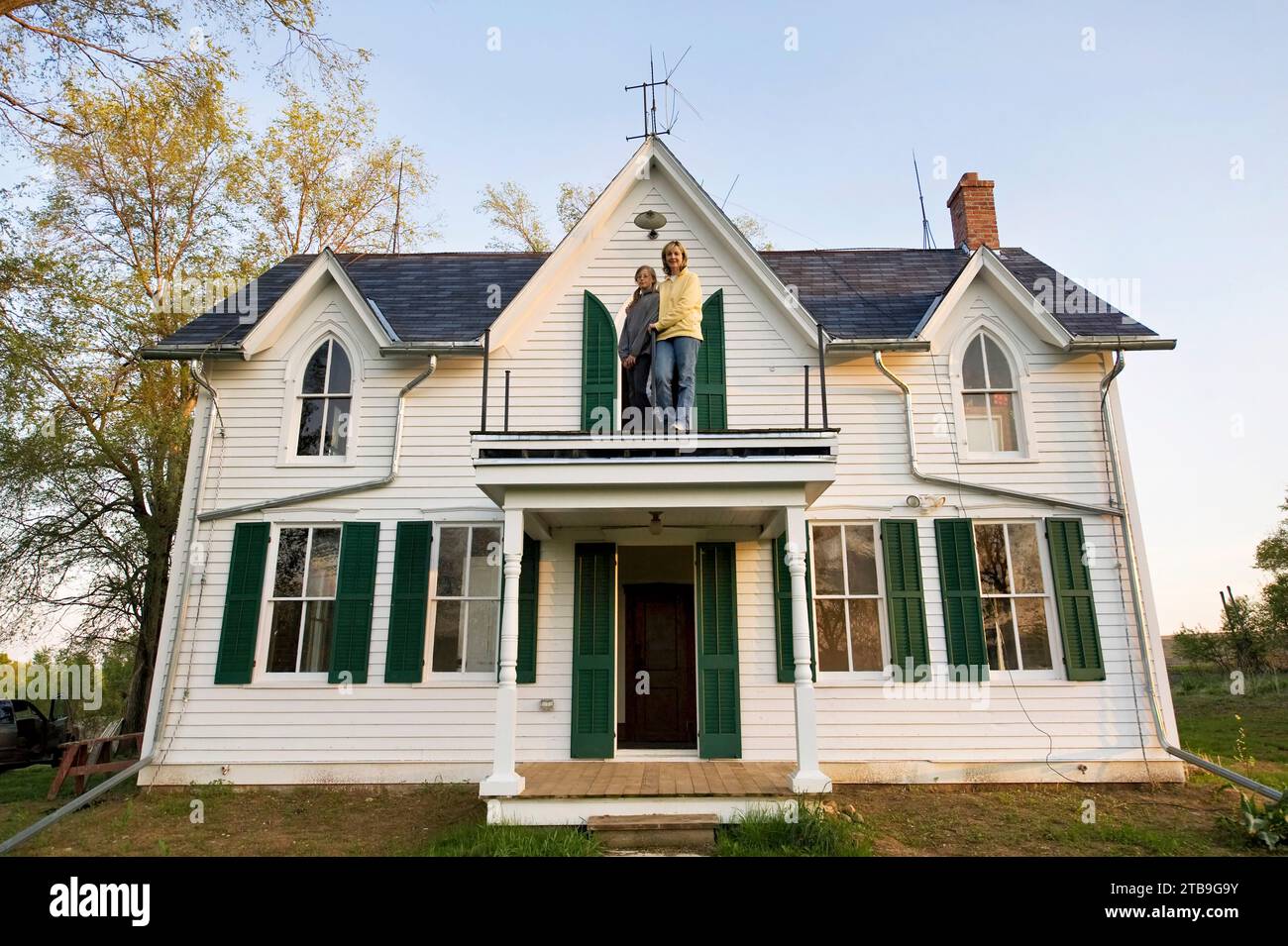 Mother and daughter stand on the balcony of a renovated farmhouse ...